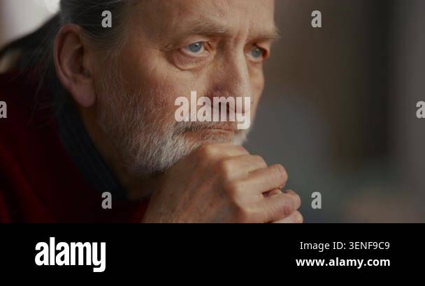 Close-up portrait of a thoughtful older man resting his hand on his ...