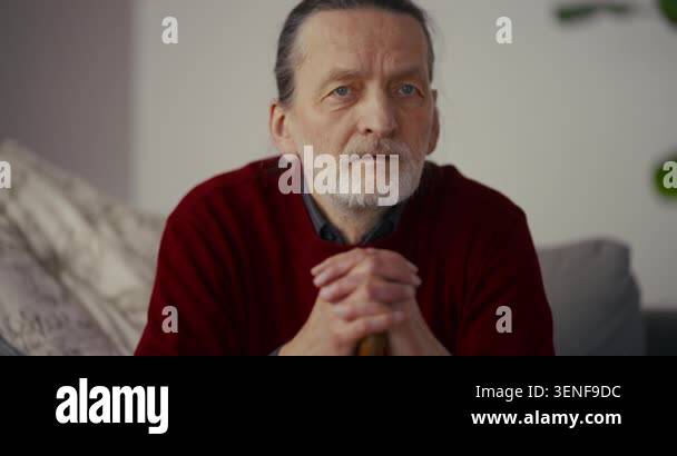 Close, contemplative portrait of an elderly bearded man in a maroon ...