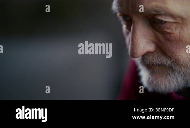 Close-up portrait of an elderly bearded man looking down with a ...