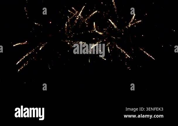 Bright golden fireworks burst against a dark night sky, spreading ...