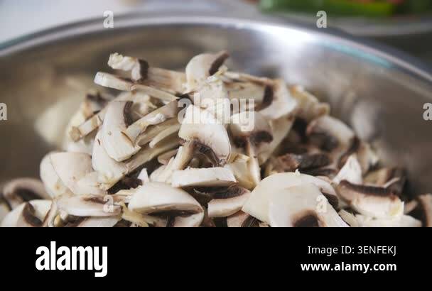 Close-up of sliced mushrooms piled in a stainless steel bowl during ...