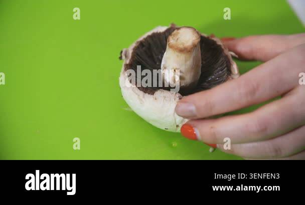 A close-up view of a sliced mushroom resting on a bright green cutting ...