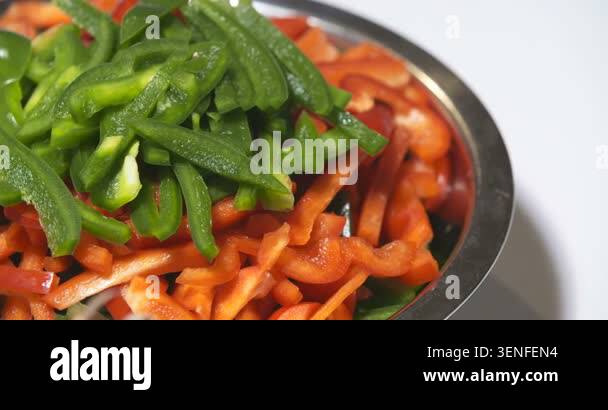 Close-up of sliced green and red bell peppers piled in a stainless ...
