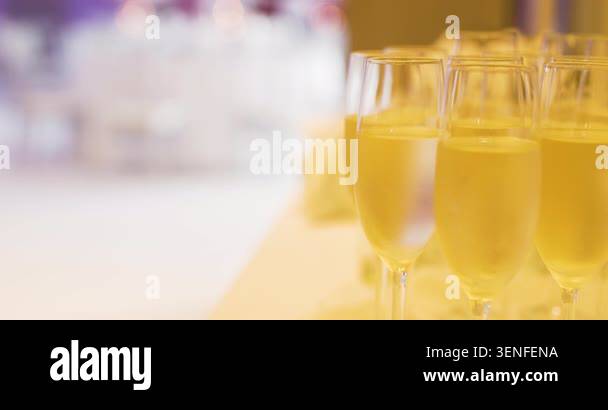 Several tall champagne flutes filled with a yellow sparkling beverage ...