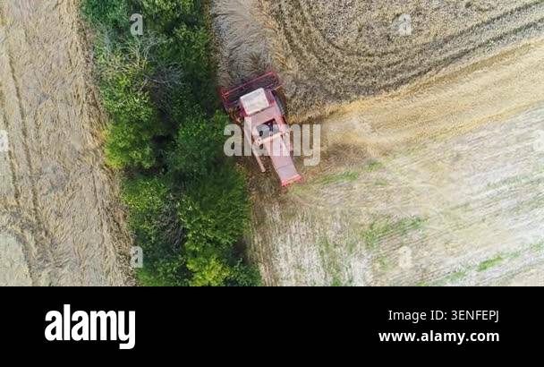 High angle view of a combine working through a golden crop field beside ...