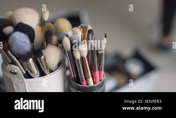 Assorted cosmetic brushes stand in containers on a table, shown in ...