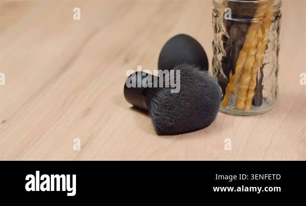 A close-up tabletop scene showing a soft makeup brush lying next to a ...
