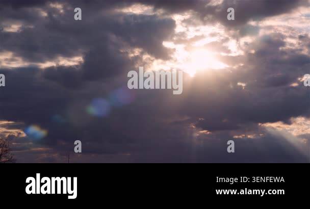 Bright sun rays shine through heavy cloud cover above a moody horizon ...