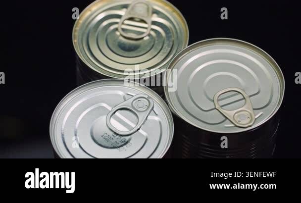 Close-up view of three sealed metal cans arranged on a dark background ...