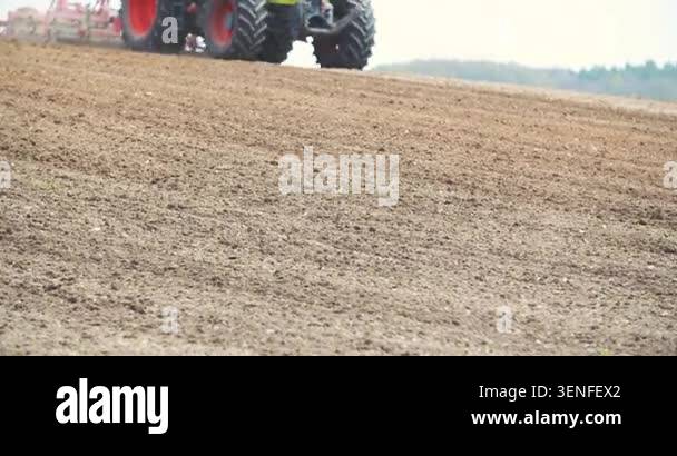 Low angle view of a large tractor moving across freshly tilled farmland ...