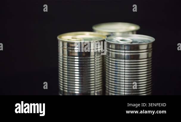 Close-up of three ribbed metal cans grouped together on a plain black ...