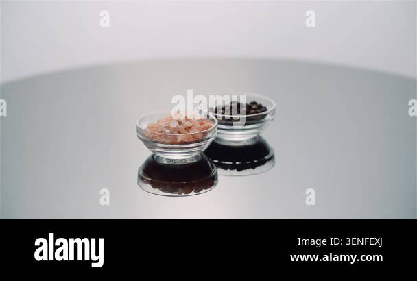 Two small glass bowls filled with pink salt crystals and dark ...