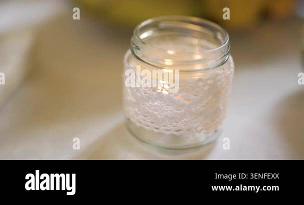 A small transparent glass jar with a decorative textured surface sits ...