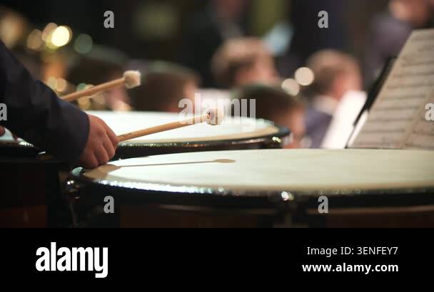 Close-up of a musician striking a timpani with a mallet during an ...