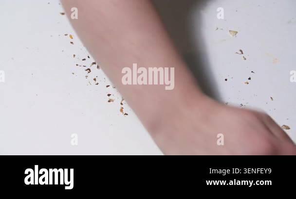 Close-up of a hand on the left side of the frame wiping small debris ...