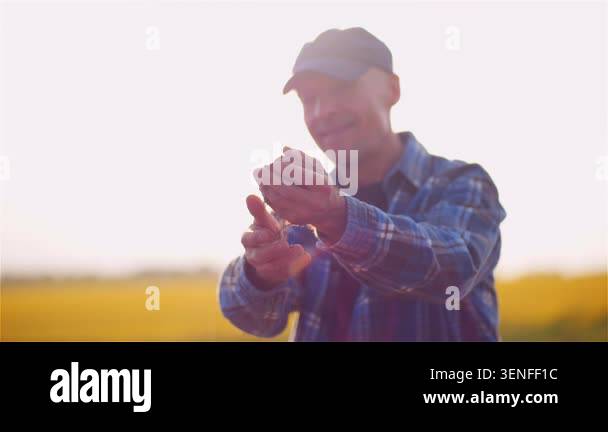 Blurred farmer in a plaid shirt and cap standing outdoors in a warm ...