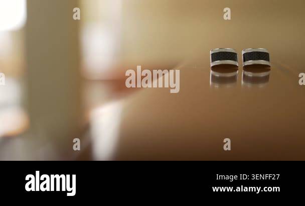 Two small metallic rings stand near the upper right on a reflective ...