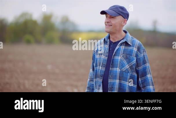 A relaxed man wearing a blue cap and plaid shirt stands in an open ...
