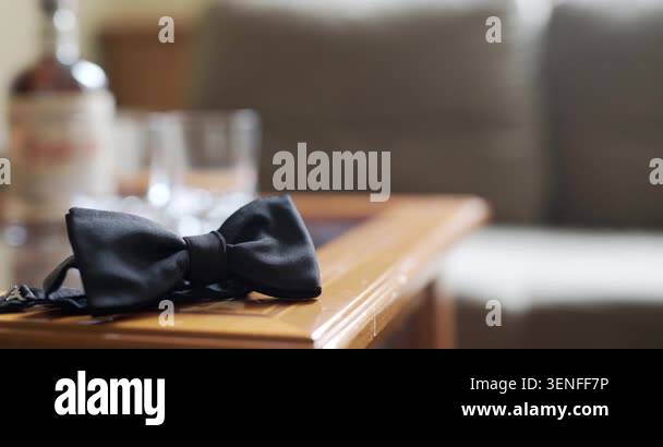 A black necktie lies on a polished wooden table in the foreground ...