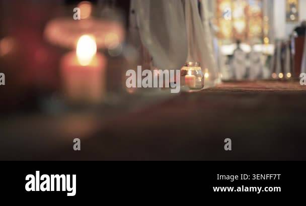 Warm candlelight glows in the foreground of a quiet religious interior ...