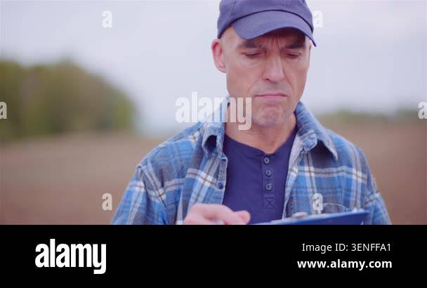 A middle-aged man wearing a blue cap and plaid shirt stands in a ...