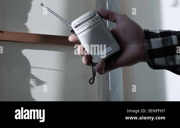 A man's hand is tuning the radio waves on the radio, listening to the ...