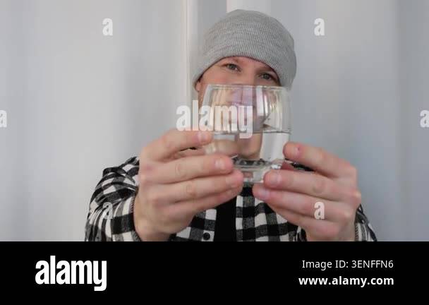 A young man with a beautiful smile drinks drinking water from a ...