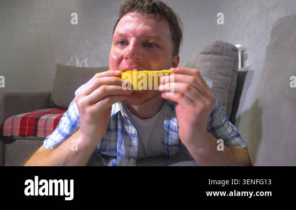 A young handsome man eats a ripe melon at home. Fruit Melon in a plate ...