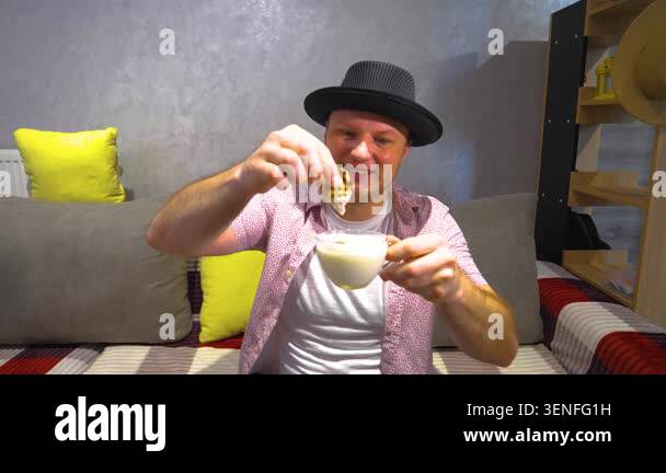 Dip dessert in yogurt and eat. Stylish man in a hat has milk for ...