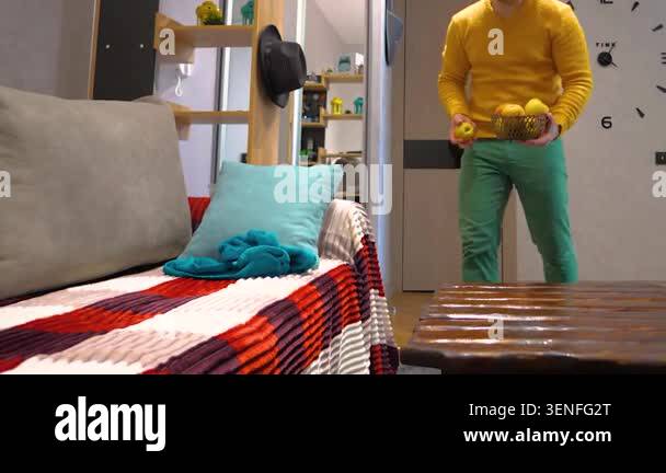 A man with apples in his hands in an apartment, a young stylish man at ...