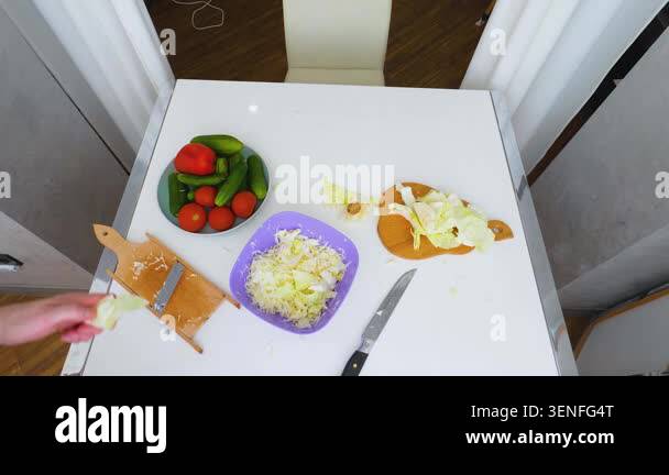A man prepares a vegetable salad, chopped white cabbage in a salad ...