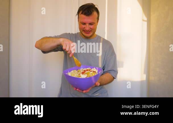 Stir the vegetable salad with a wooden spoon. A young man prepares a ...