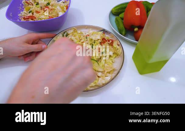Stir the vegetable salad with a wooden spoon. A young man prepares a ...