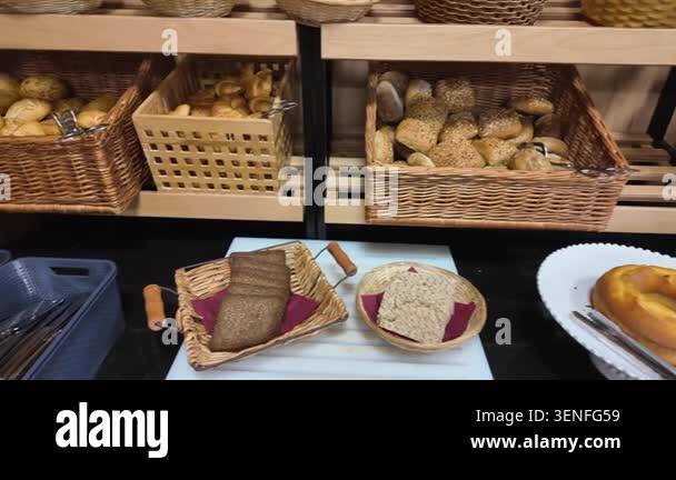 Variety of sliced rye bread, whole grain buns, and pastry displayed in ...
