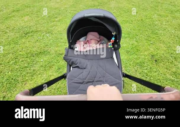 POV close up shot of a parent hand pushing a modern grey baby stroller ...