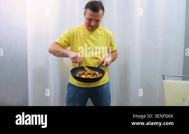 A man is preparing an omelette with fried tomatoes in a frying pan ...