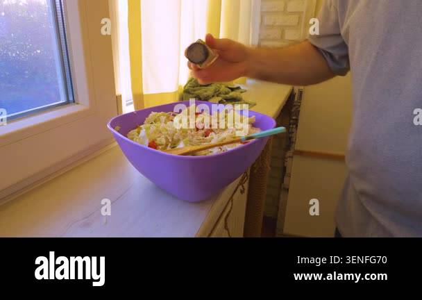 A man prepares a salad from vegetables and fresh cabbage. Cooking food ...
