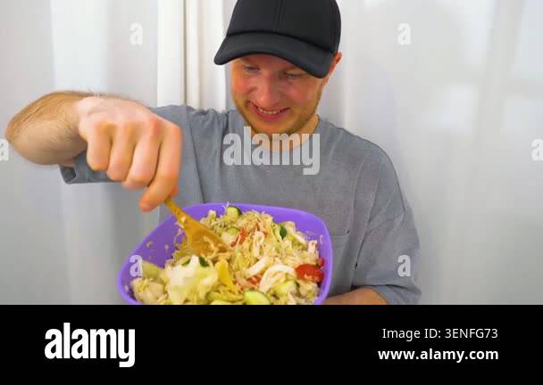 Stir the fresh salad with a wooden spoon. A man prepares a salad of ...