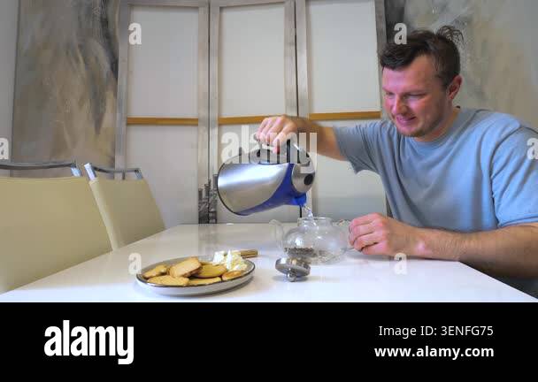 Brew tea in the kitchen at home, pour boiling water into the teapot ...