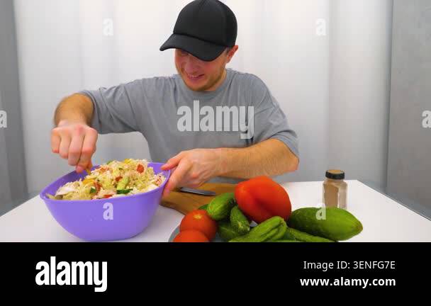 Season the salad with ground pepper. A man prepares a salad of ...