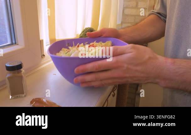 A man prepares a salad from vegetables and fresh cabbage. Cooking food ...