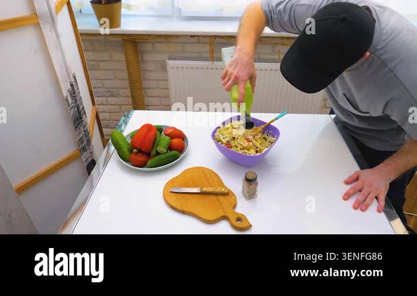 Drizzle olive oil over fresh salad. A man prepares a salad of ...