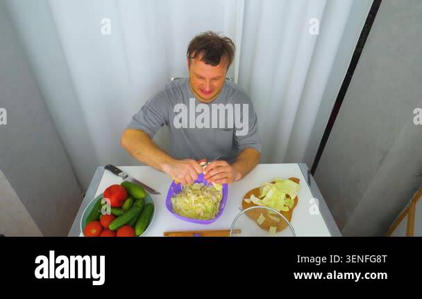 A man prepares a vegetable salad, chopped white cabbage in a salad ...
