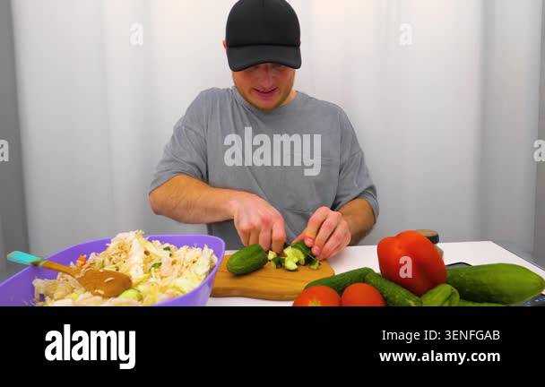 Cut cucumbers with a knife. A man prepares a salad of vegetables and ...