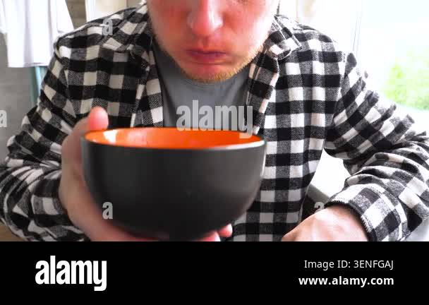 A man eats homemade food from a plate. Drink soup from a plate. Slow ...