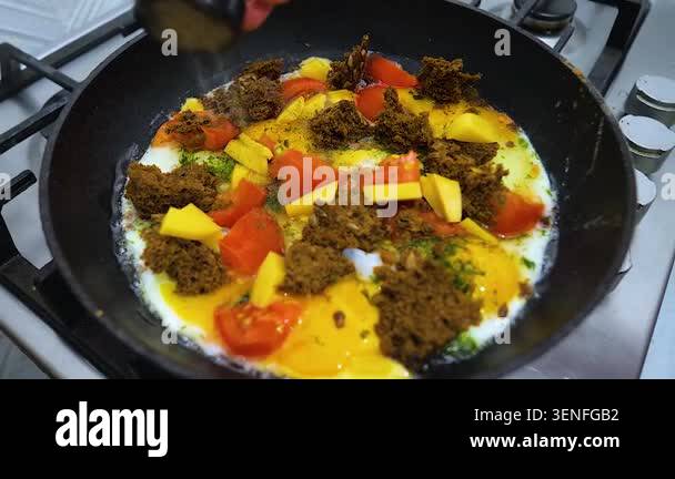 Pepper the omelet with tomatoes in a frying pan. Cooking food in a ...