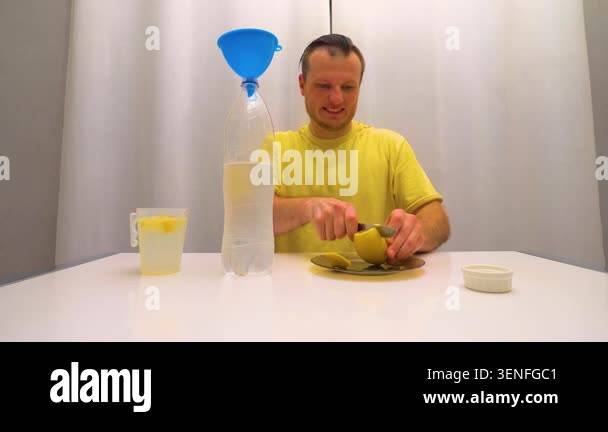A man squeezes juice from a lemon, adding natural lemon juice to ...