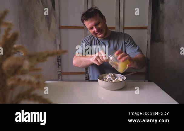 Pour honey into a plate and mix with cottage cheese, young man at the ...