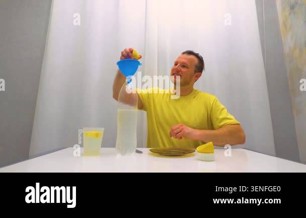 A man squeezes juice from a lemon, adding natural lemon juice to ...