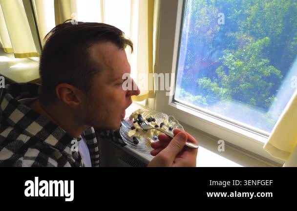 Eating cottage cheese with blue berries, a man eats white cheese while ...